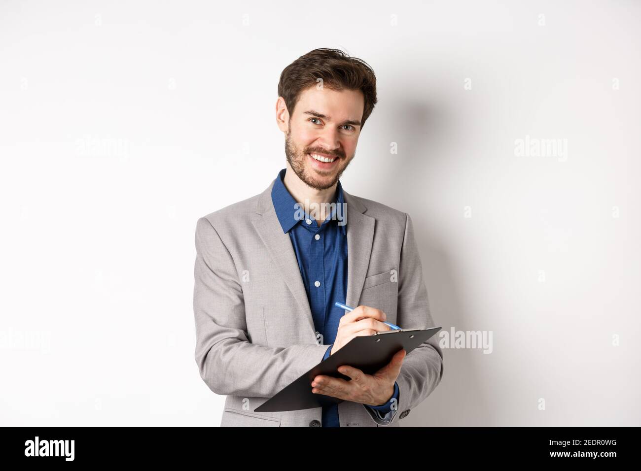 Smiling male manager in suit writing on clipboard, taking notes at ...