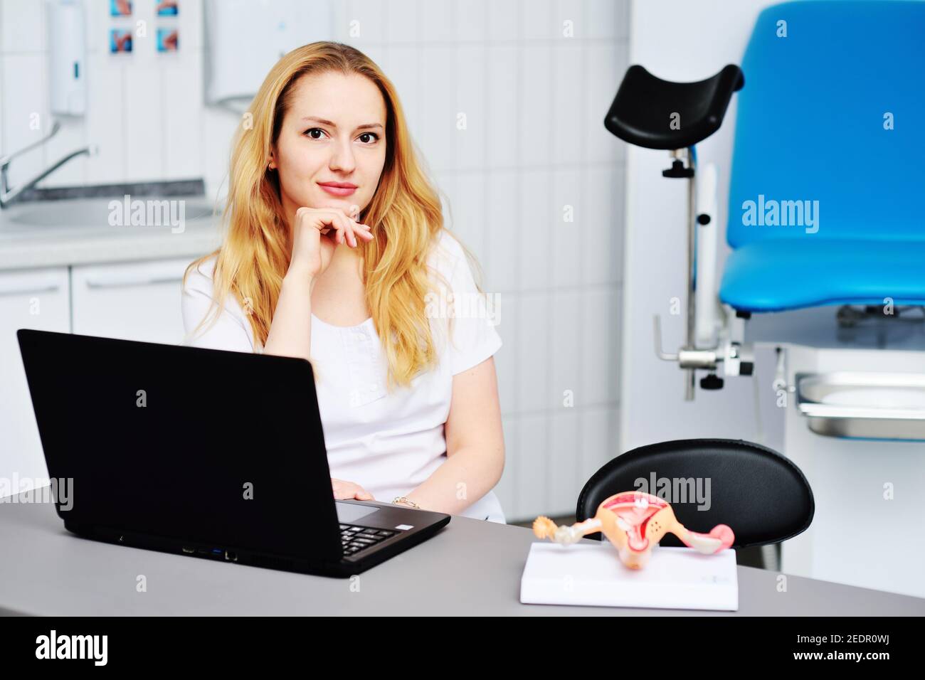 a young woman gynecologist at the workplace with a laptop and an ...