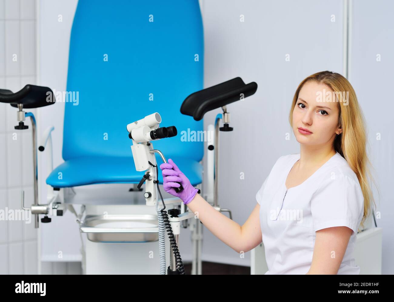 Young Attractive Female Gynecologist Holding A Colposcope Or Microscope Against The Background