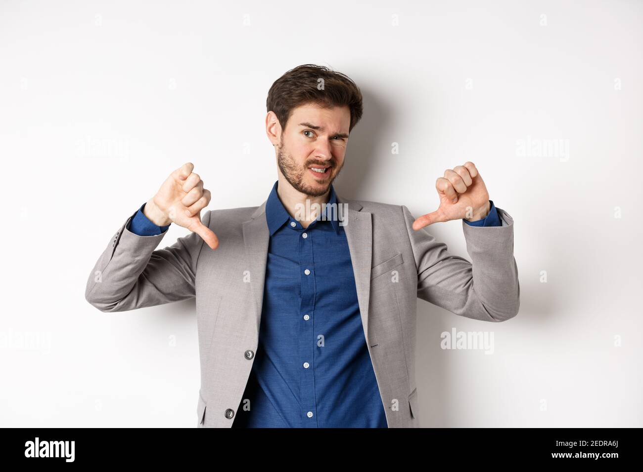 It sucks. Man feeling awkward showing thumbs down and judging something ...