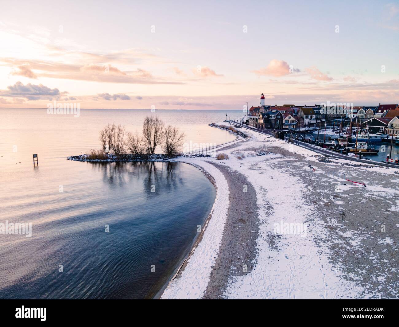 snow covered beach during wnter by Urk lighthouse in the Netherlands ...