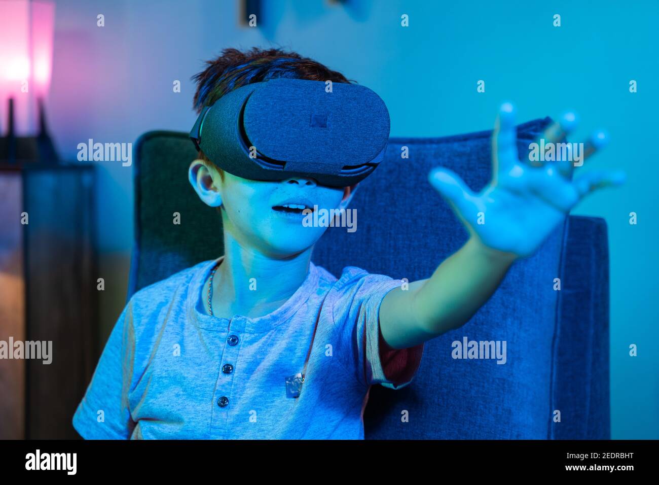 Young kid with VR or virtual reality headset feeling or enjoying the ...