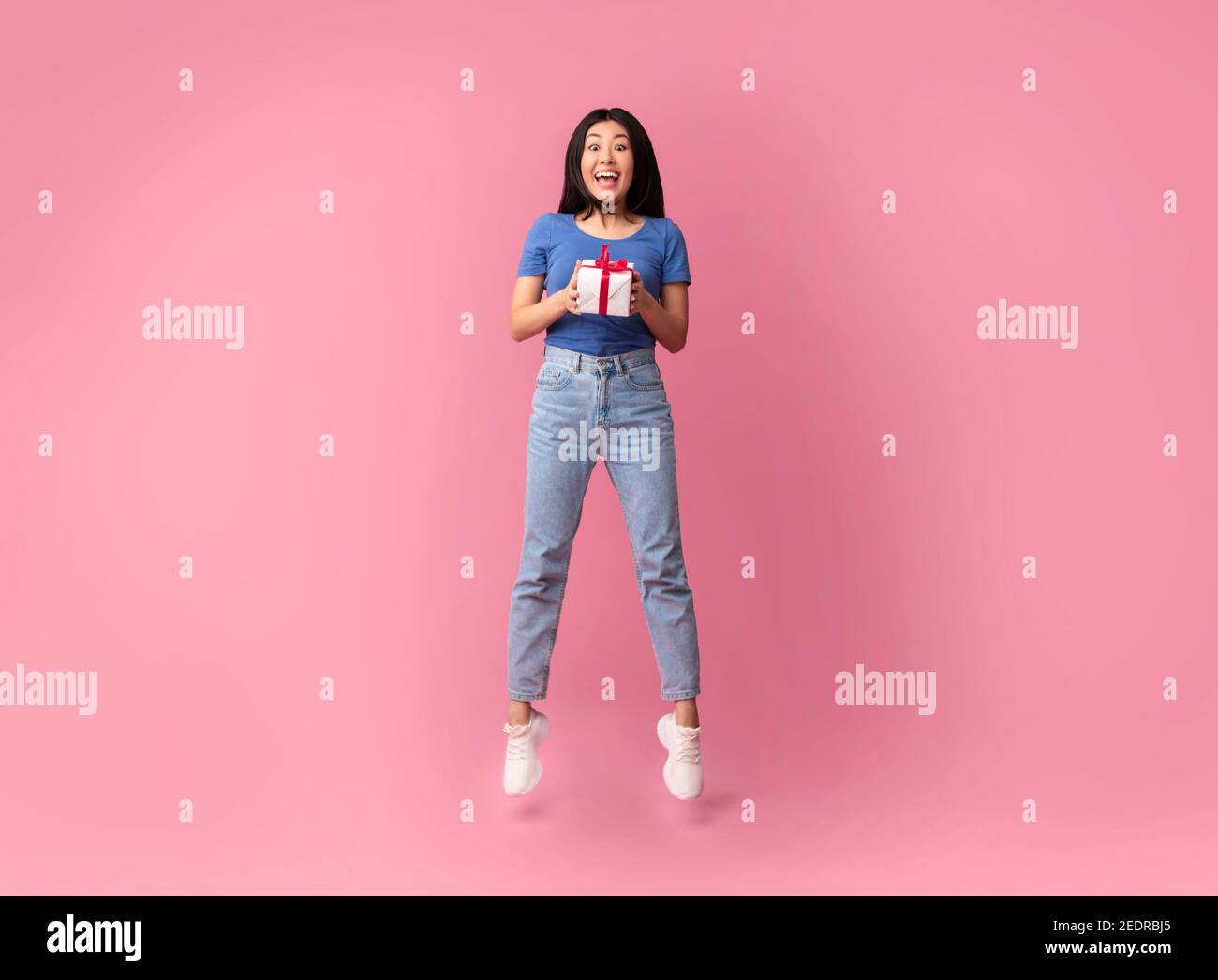 Jumping excited asian lady holding and giving present box Stock Photo ...