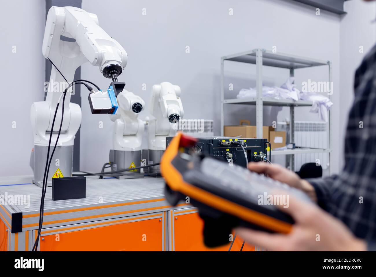 Engineer operator controls automatic mechanical robot arm to weld and collect car parts Stock ...