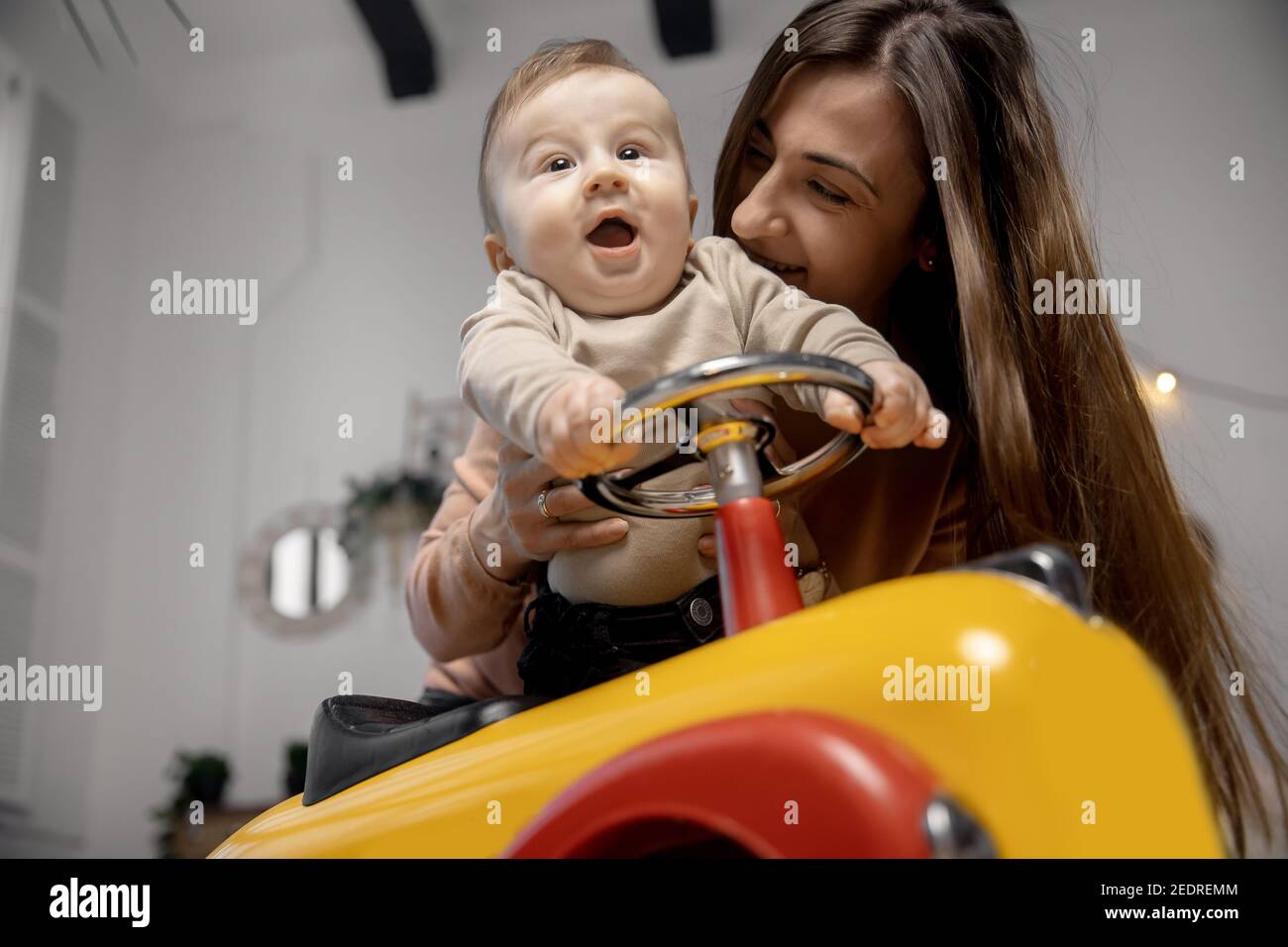 Concept Young baby driver. Mother plays with her little son and big toy ...