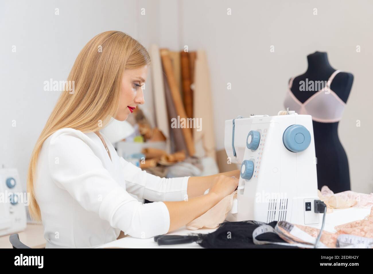 Caucasian young woman tailor works on sewing machine Stock Photo - Alamy
