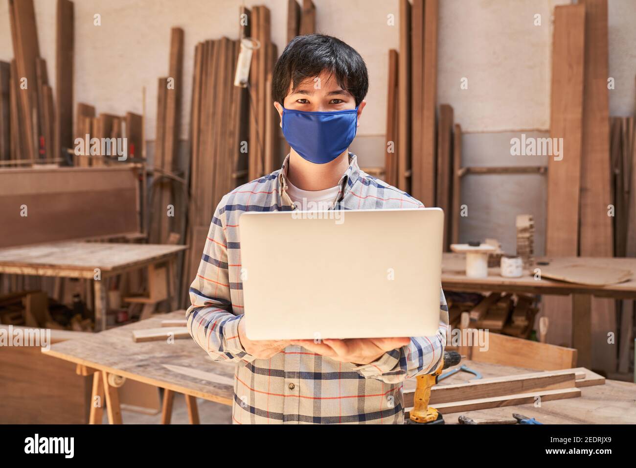 Craftsman apprentice with face mask because of Covid-19 with laptop ...