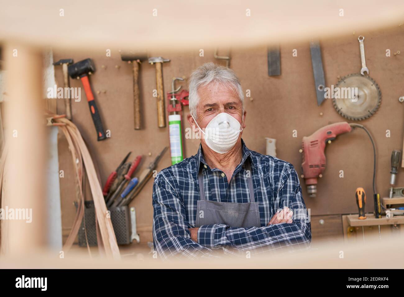Master craftsman with mask because of Covid-19 in his workshop with a ...