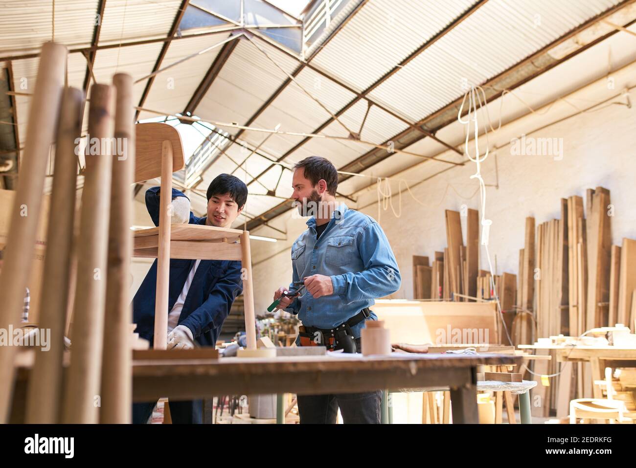 Cabinet maker trainee and trainer build a chair in the joinery workshop ...