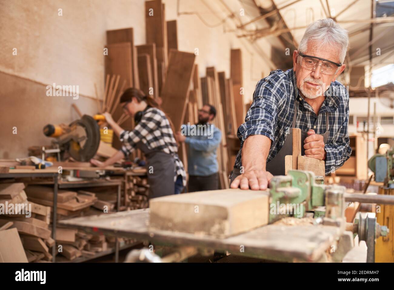 Senior craftsman as a carpenter in the carpentry workshop while planing ...