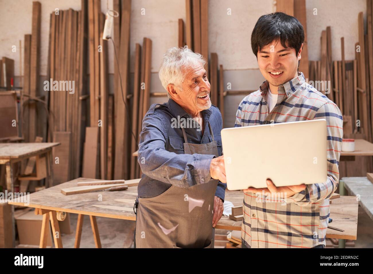 Young web designer and senior craftsman plan the carpenter's website ...