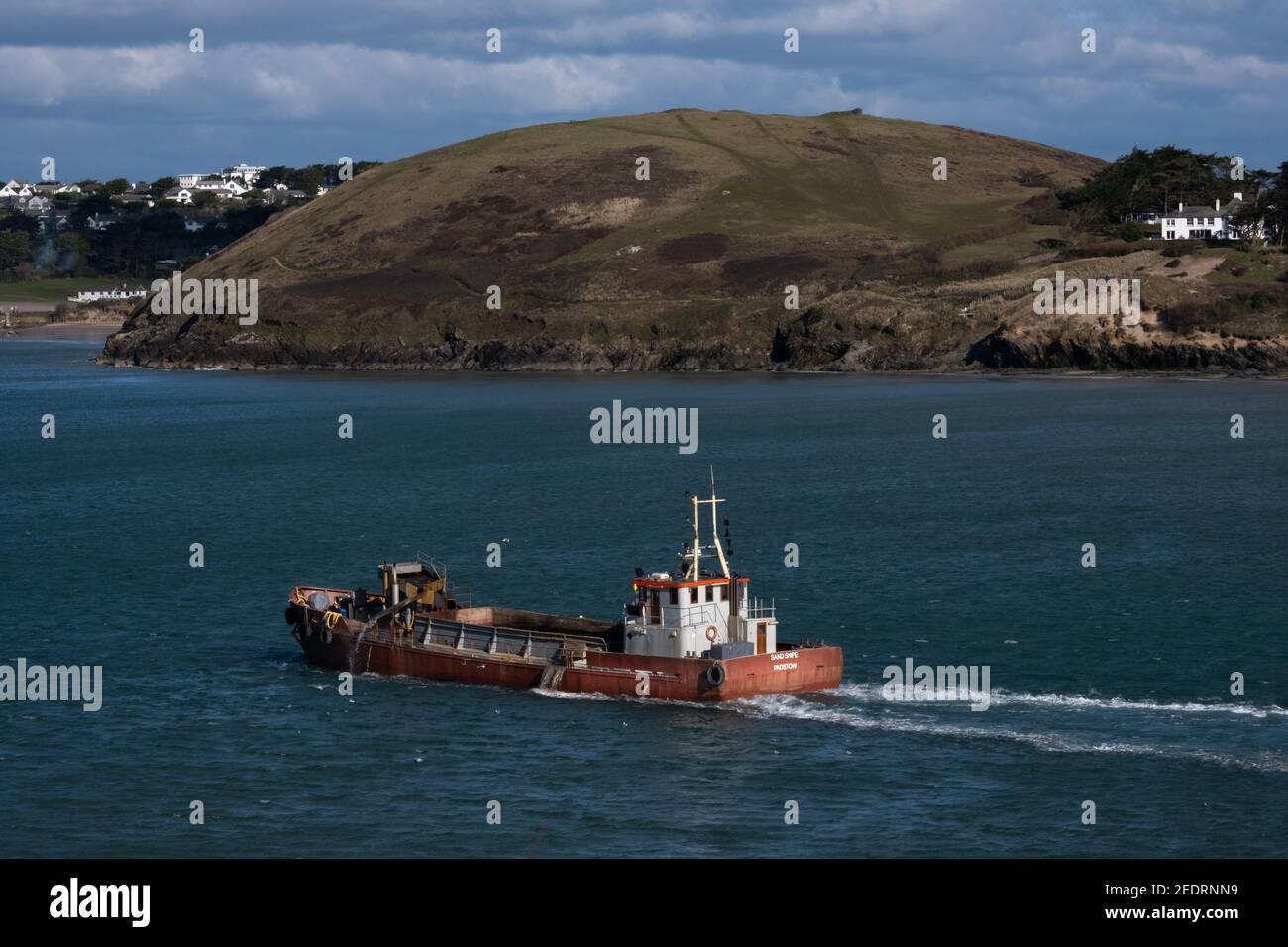 red low lying dredging ship leaving Padstow harbour whilst pumping ...