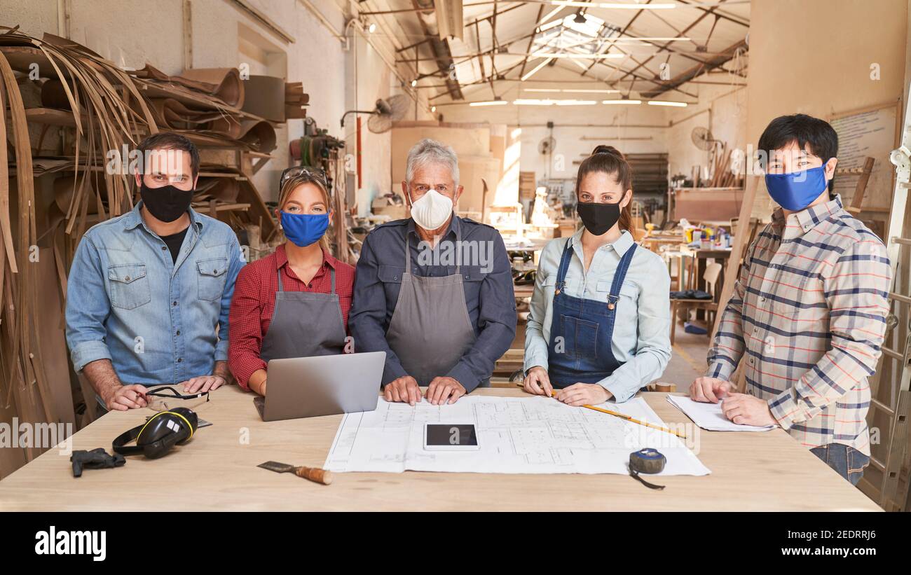 Group of craftsmen with face masks because of Covid-19 in the carpentry ...