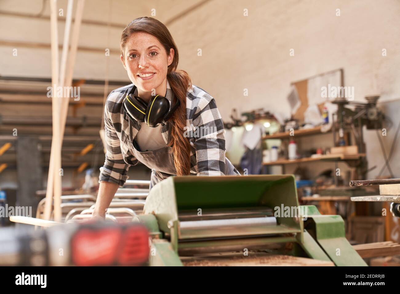 Woman as a craftsman trainee works on the thicknesser in the joinery ...