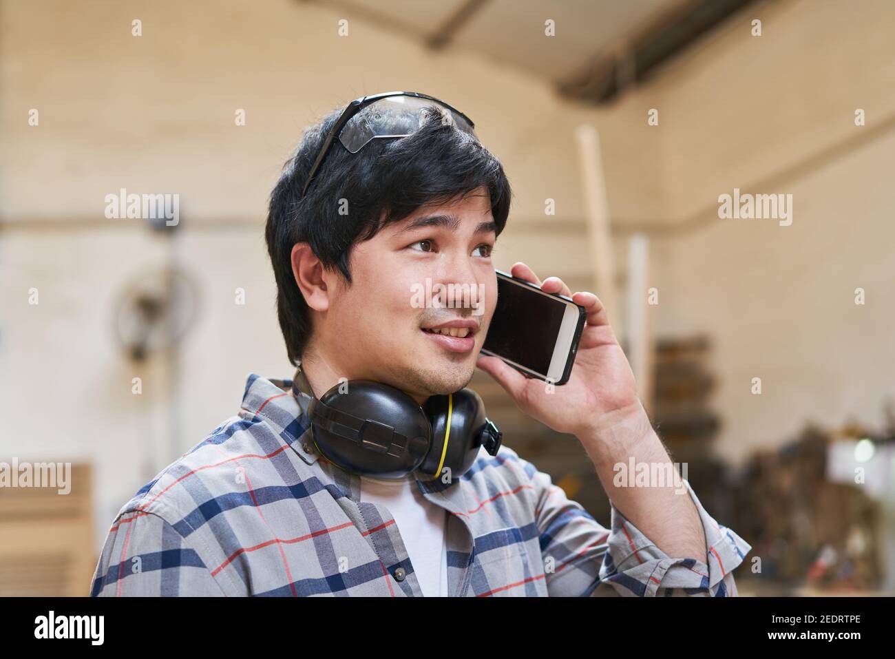 Craftsman as a carpenter trainee calls with the smartphone in the ...