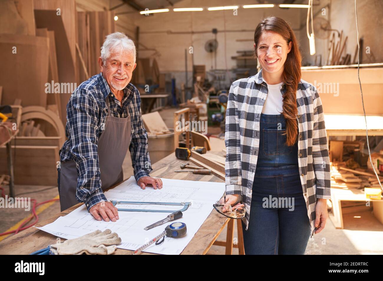 Senior craftsman and woman as apprentice in training in the carpentry ...