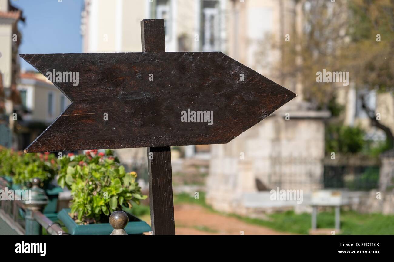 Direction arrow sign. Empty wooden pointer on a pole, blur city center ...