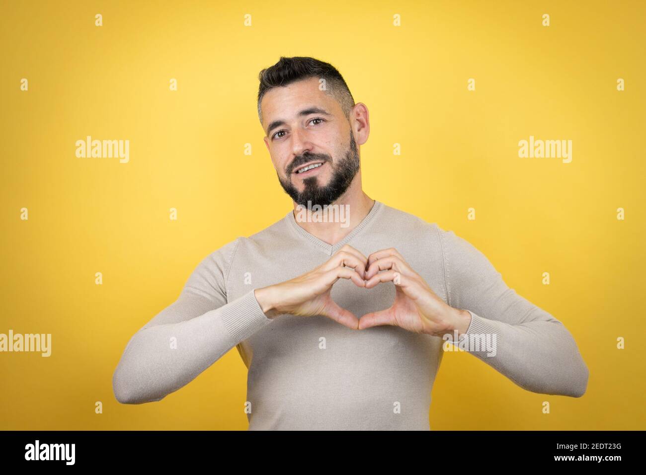 Handsome man with beard wearing sweater over yellow background smiling ...