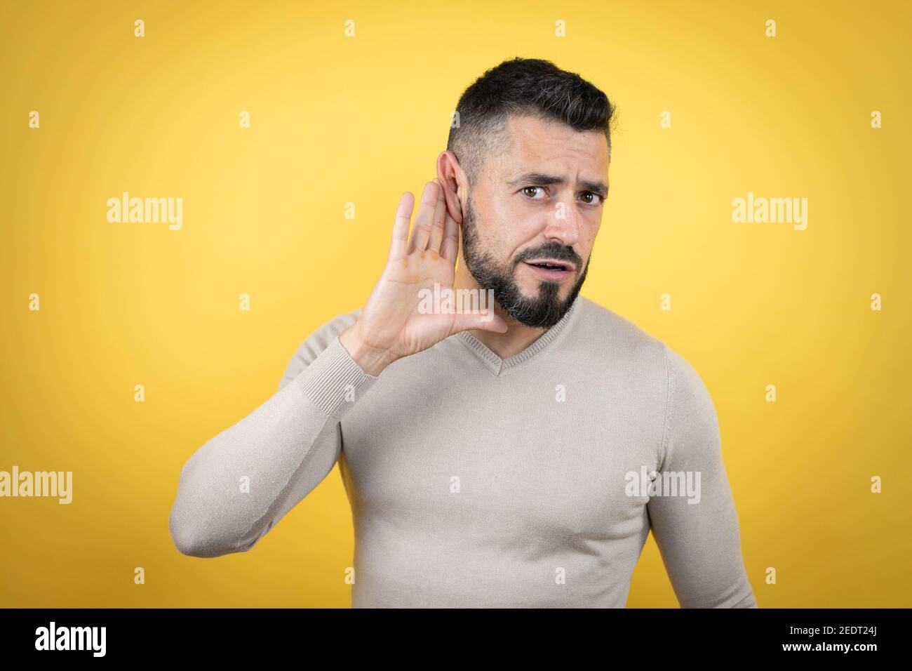 Handsome man with beard wearing sweater over yellow background ...