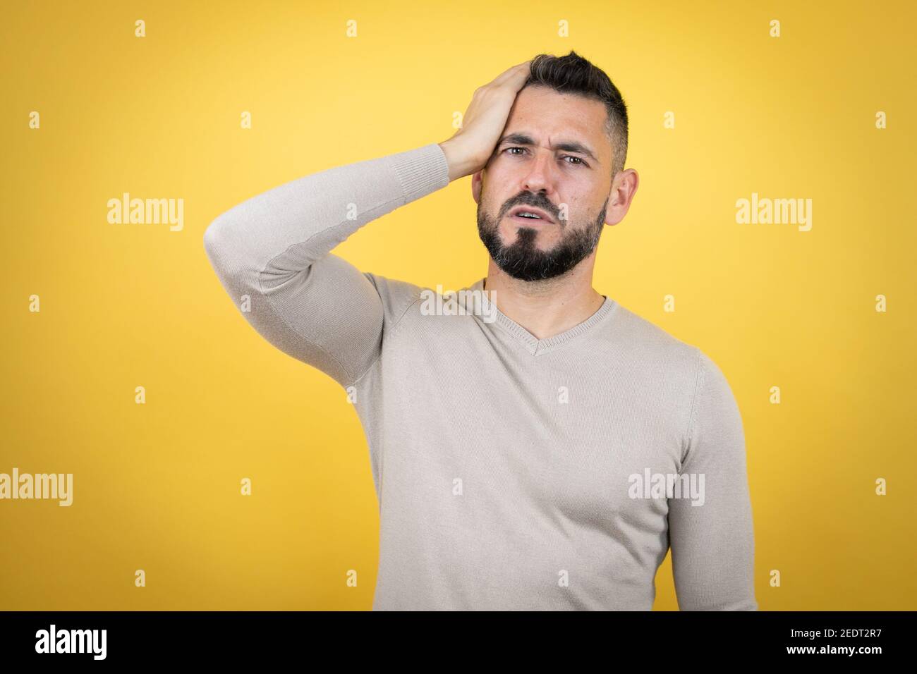 Handsome man with beard wearing sweater over yellow background putting ...