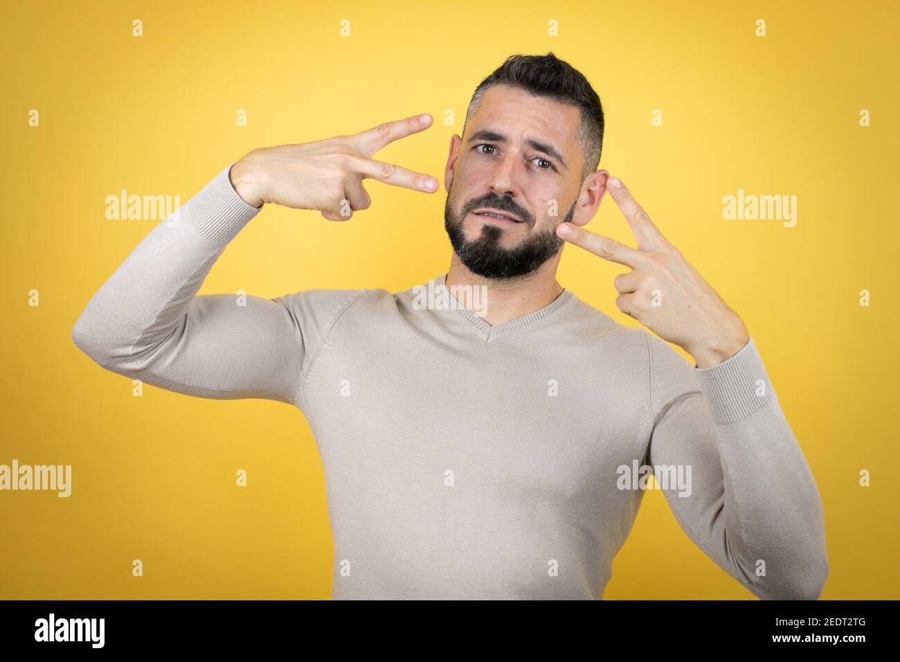 Handsome man with beard wearing sweater over yellow background Doing ...