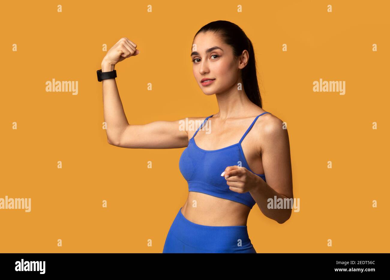 Confident woman showing biceps and pointing to camera Stock Photo - Alamy