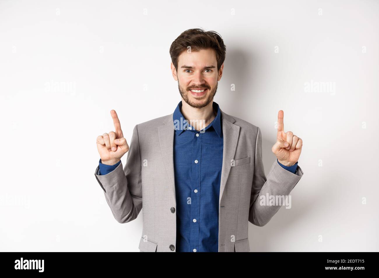 Confident successful businessman pointing fingers up, smiling and ...