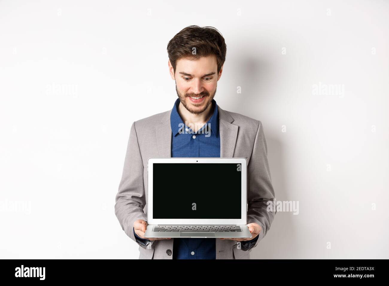 Handsome caucasian businessman in suit showing empty laptop screen ...
