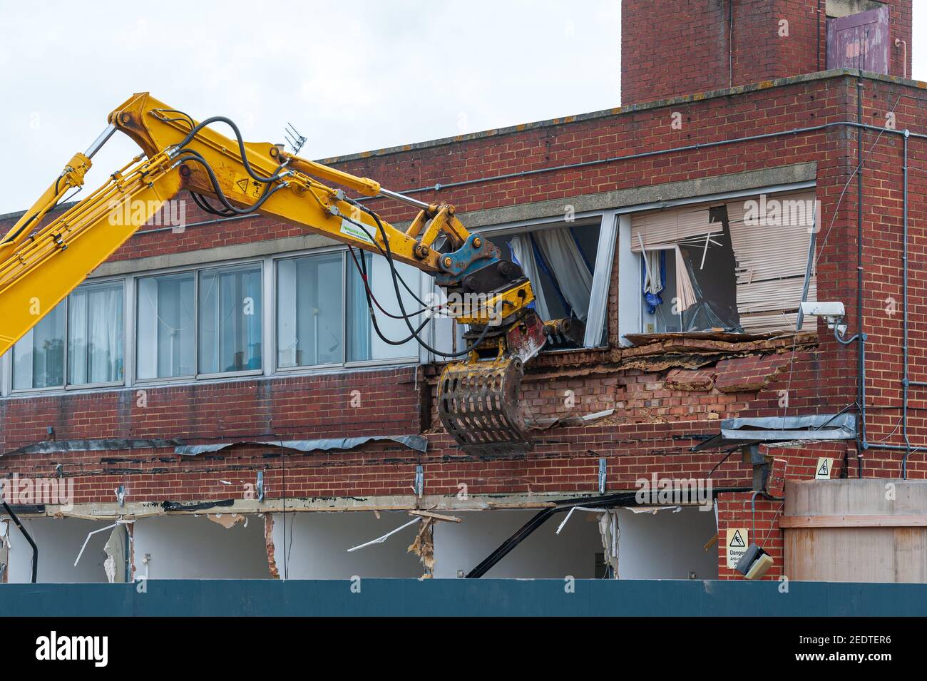 Demolition of an old building with a long reach machine hydraulic jaw ...