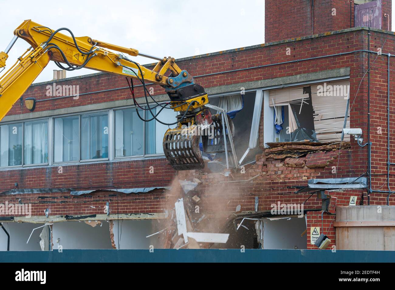 Demolition of an old building with a long reach machine hydraulic jaw ...