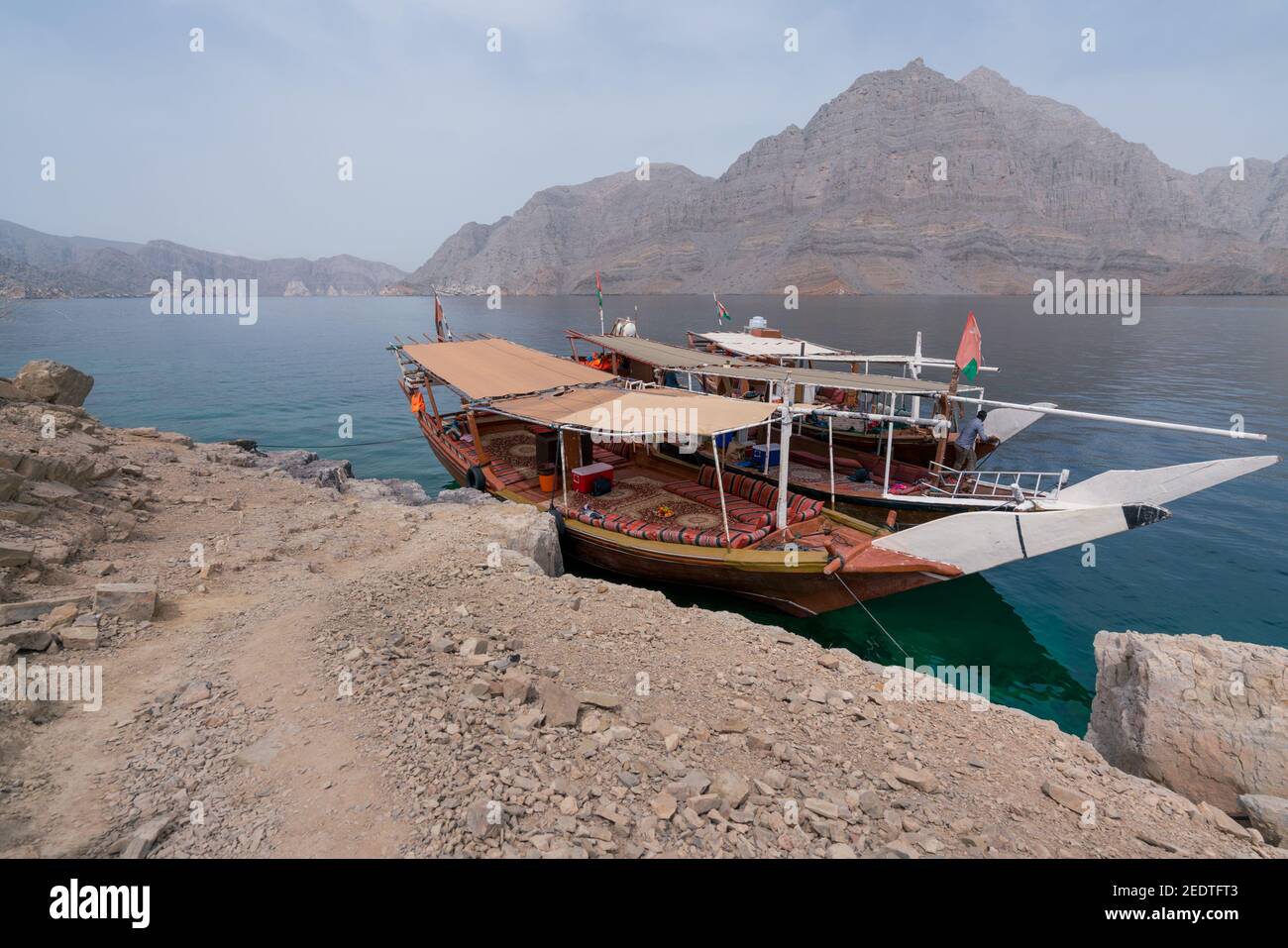 Two traditional arab dhow boats parked by an island in turquoise fjords ...