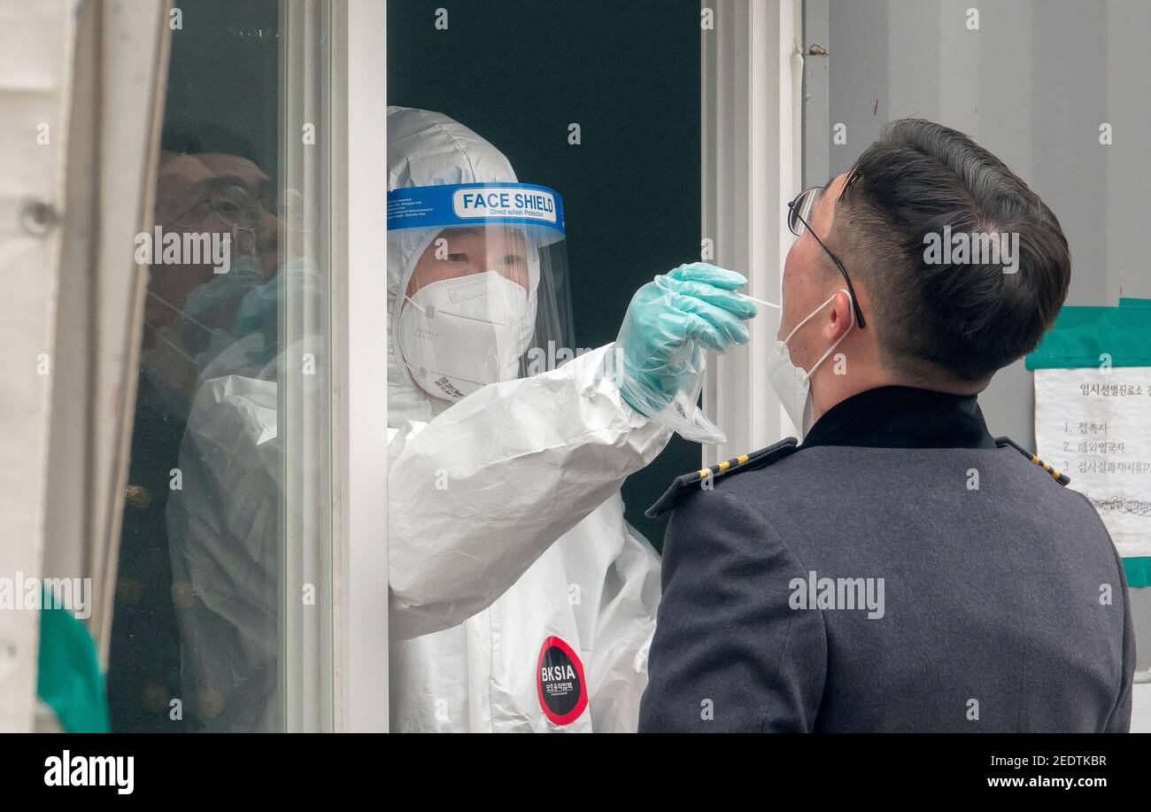 A nurse wearing a personal protective equipment suit (PPE) takes a swab ...