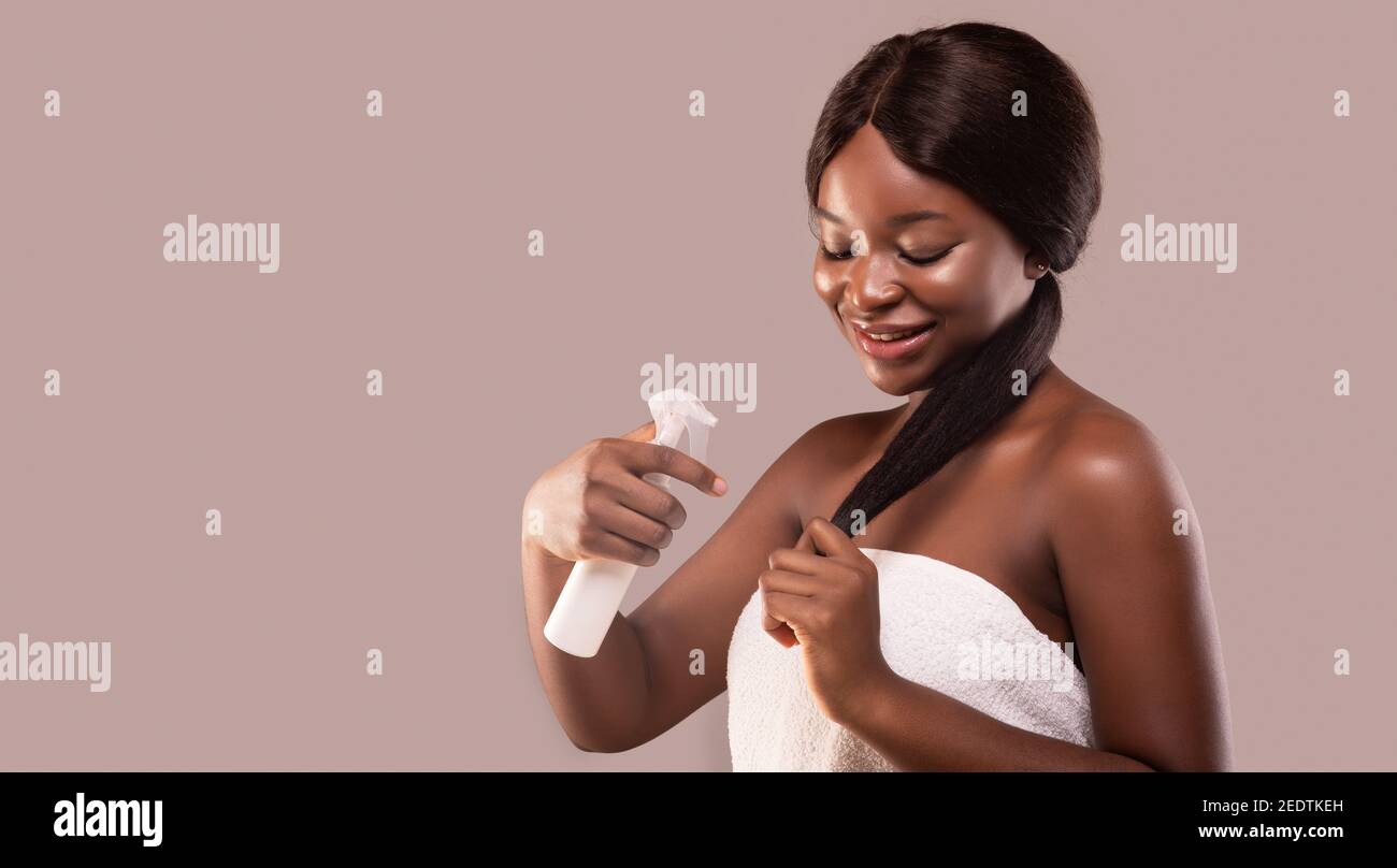Smiling Black Lady Applying Moisturising Hair Spray, Making Split Ends ...