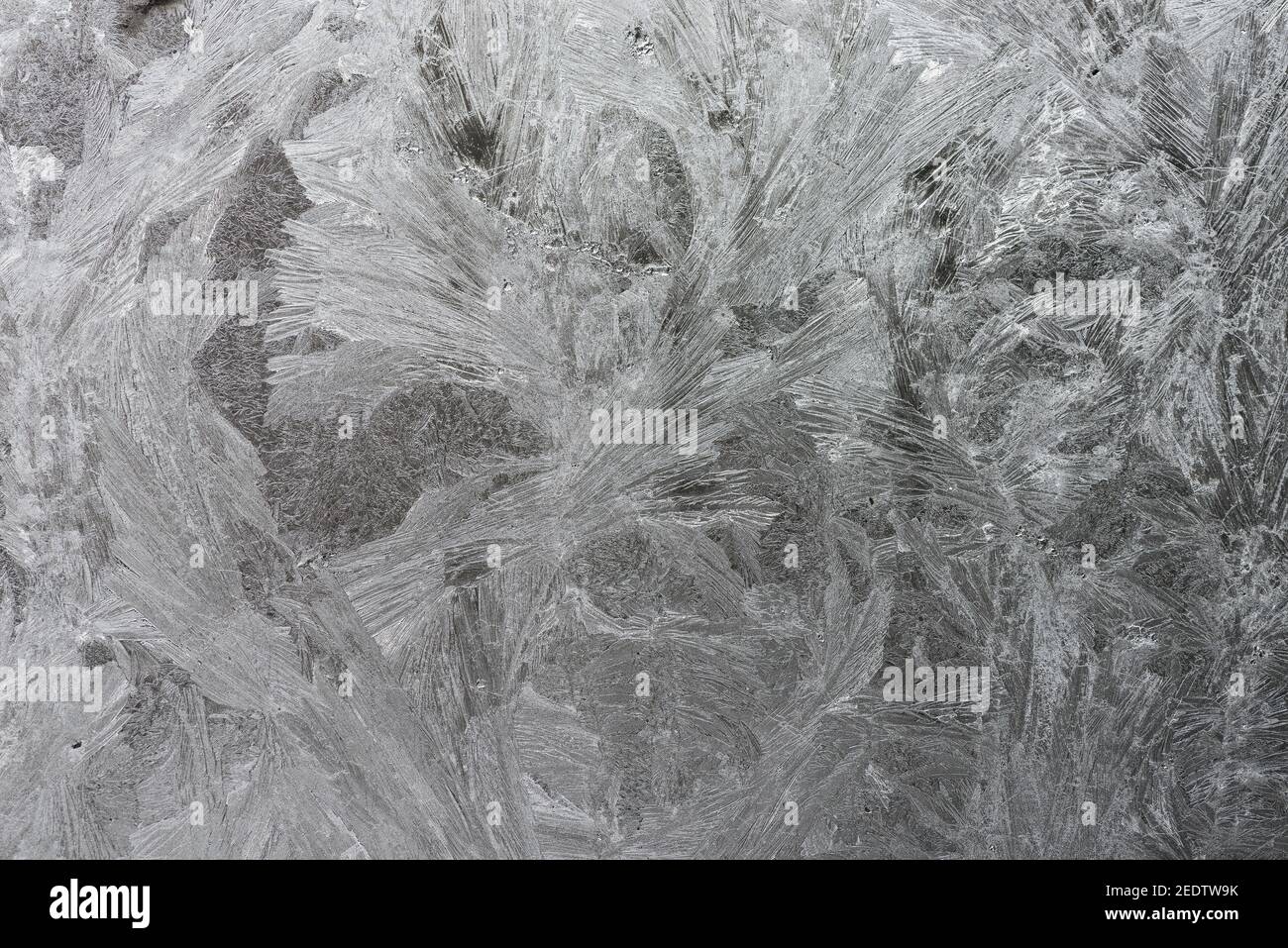 Frozen ice coated window pane with patterns left by coating crystals ...