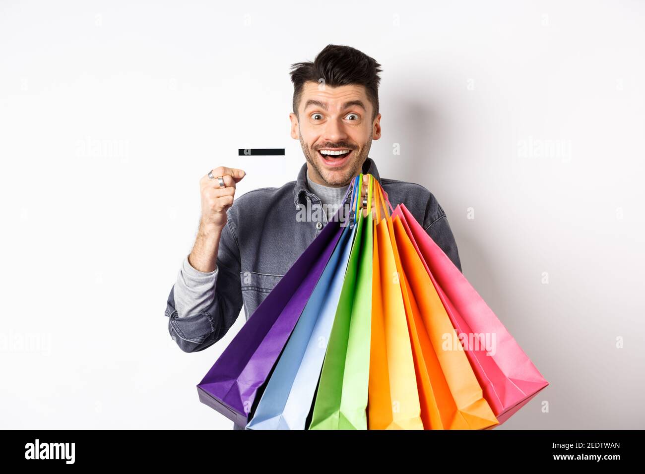 Happy guy shopaholic holding colorful shopping bags and showing plastic ...