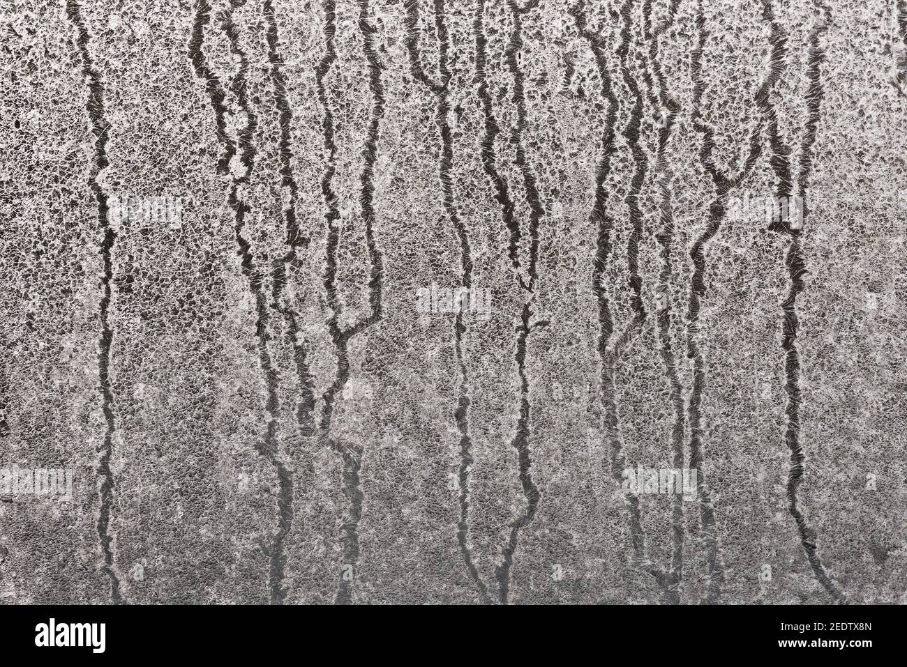 Frozen ice coated window pane with patterns left by coating crystals ...