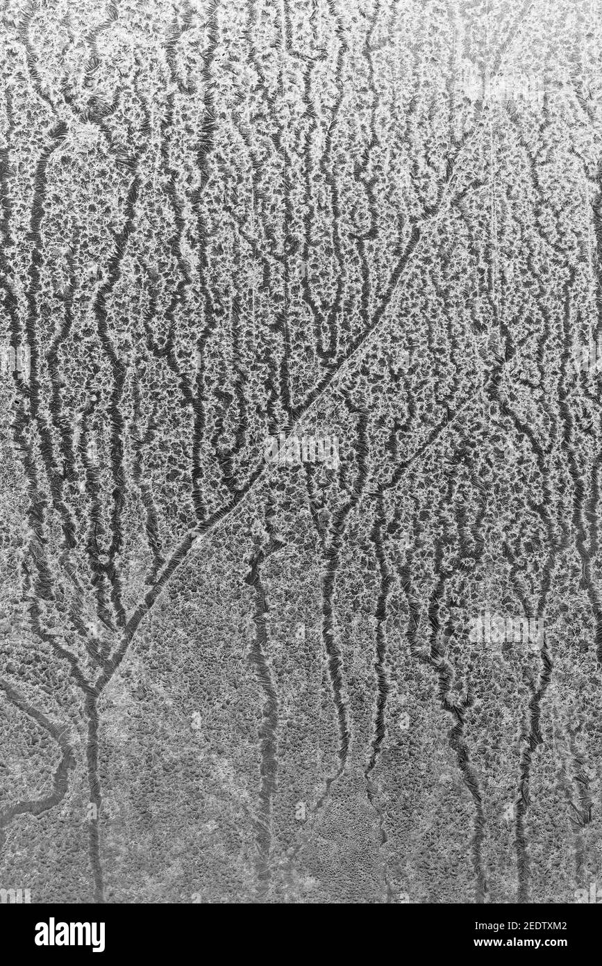 Frozen ice coated window pane with patterns left by coating crystals ...