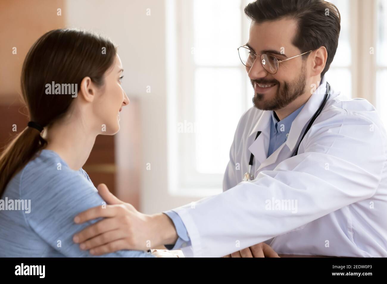 Smiling 35s male doctor telling good news to patient Stock Photo - Alamy