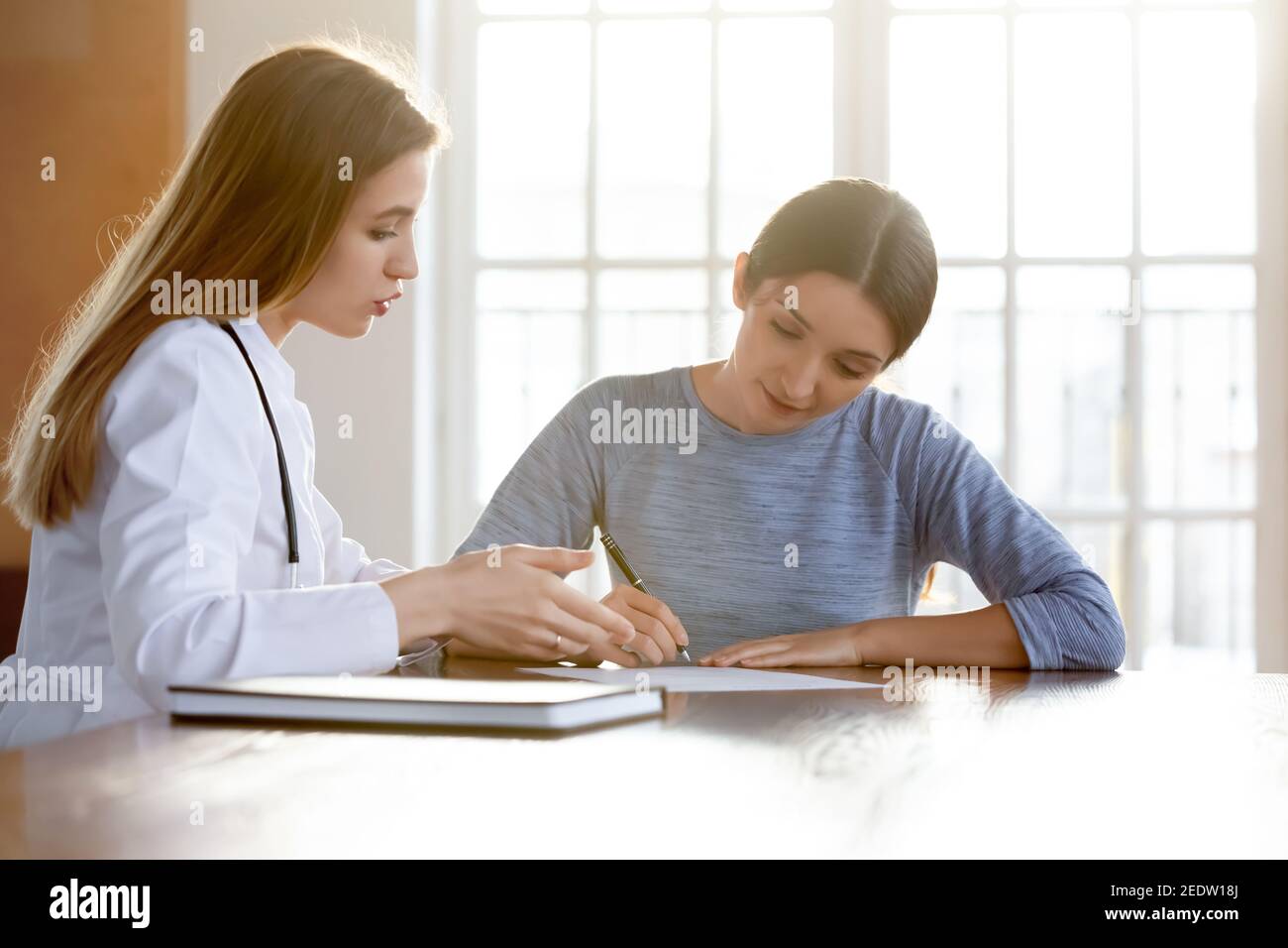 Focused young doctor explaining health insurance agreement details to ...