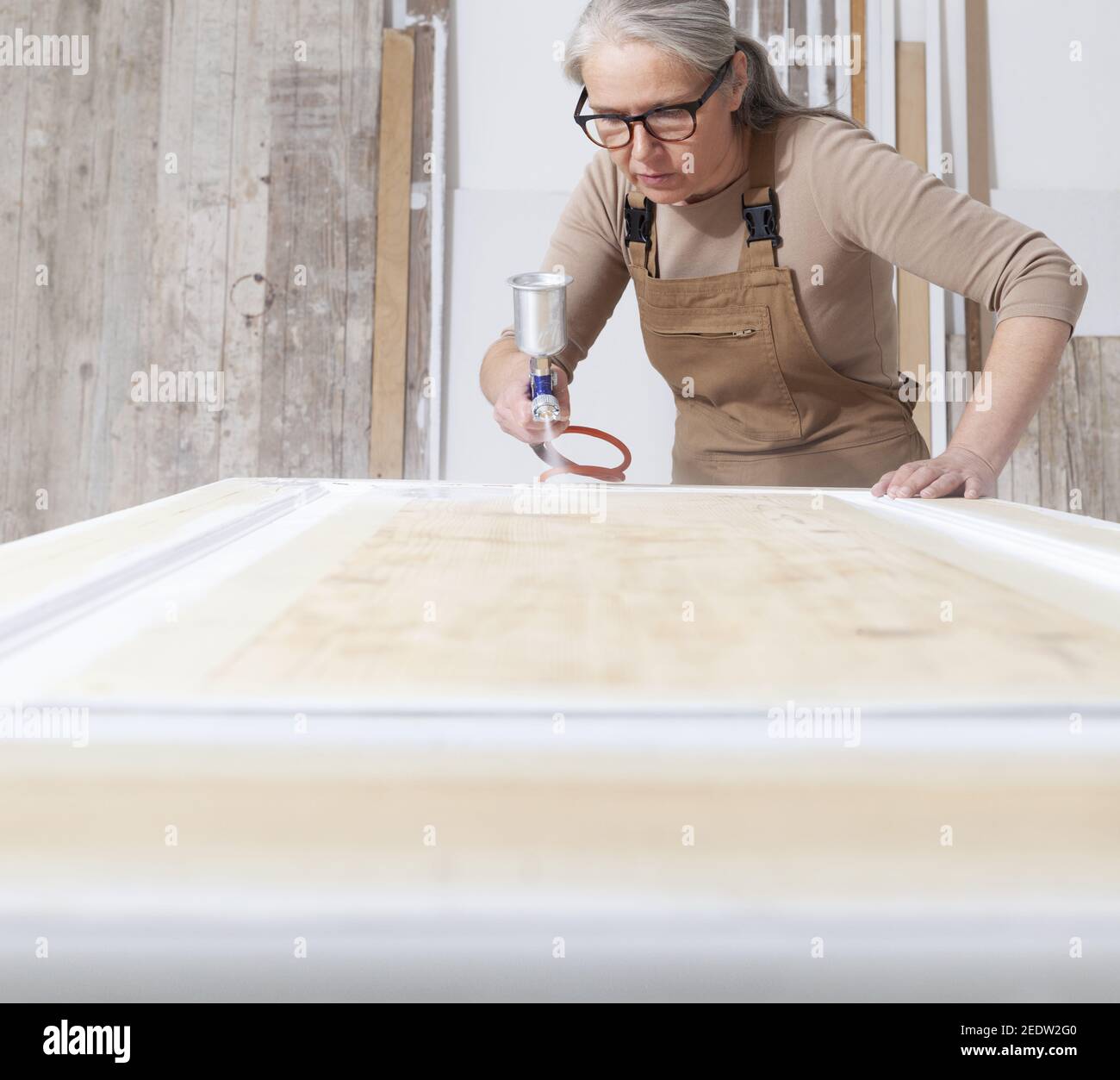 wood crafts, woman artisan carpenter painting with spray gun paint ...