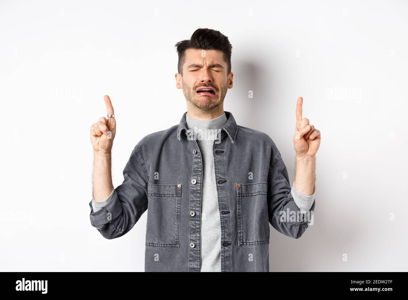 Sad and miserable guy crying while pointing fingers up, showing ...