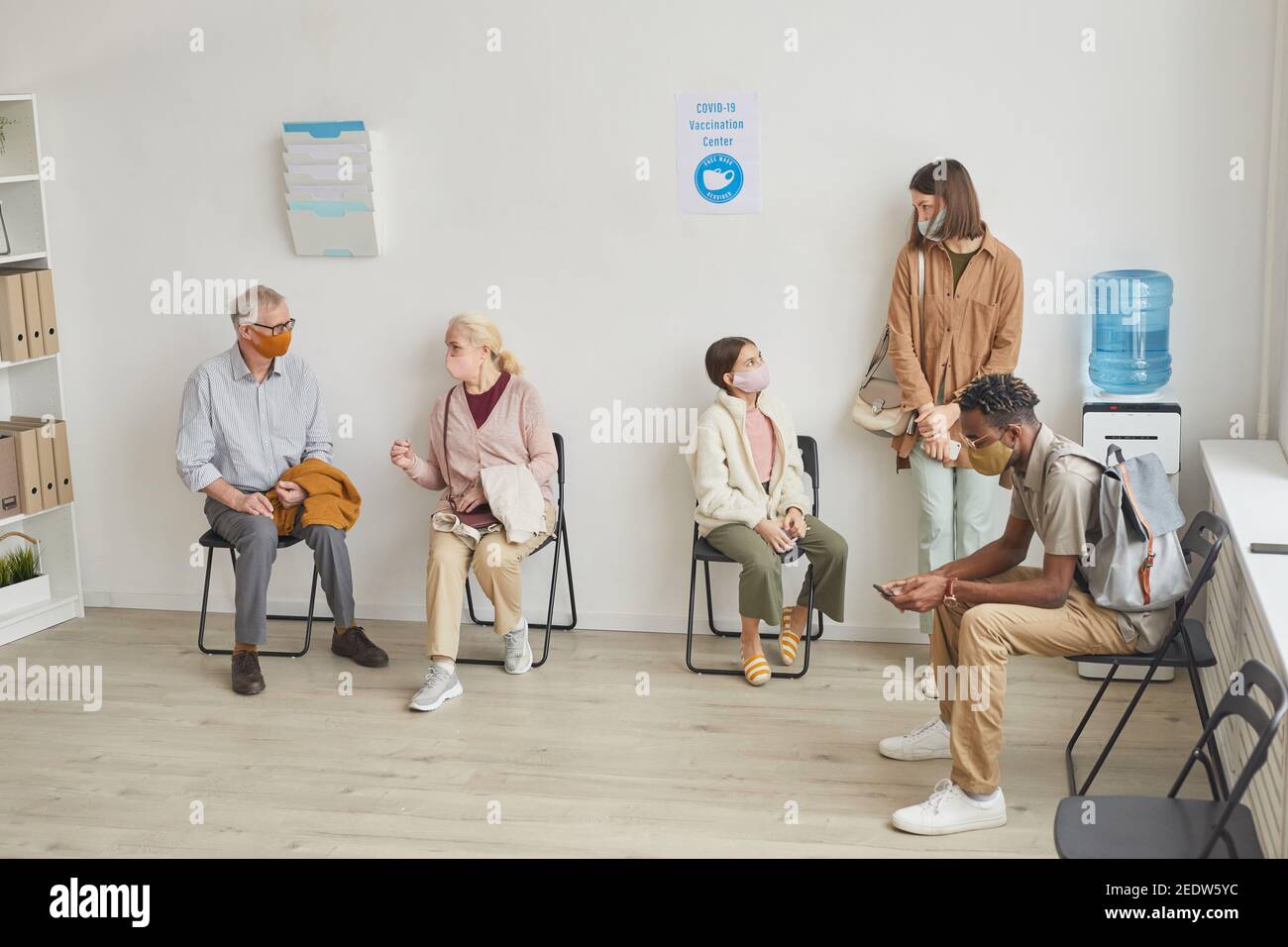 Wide angle view at hospital waiting room with diverse group of people ...