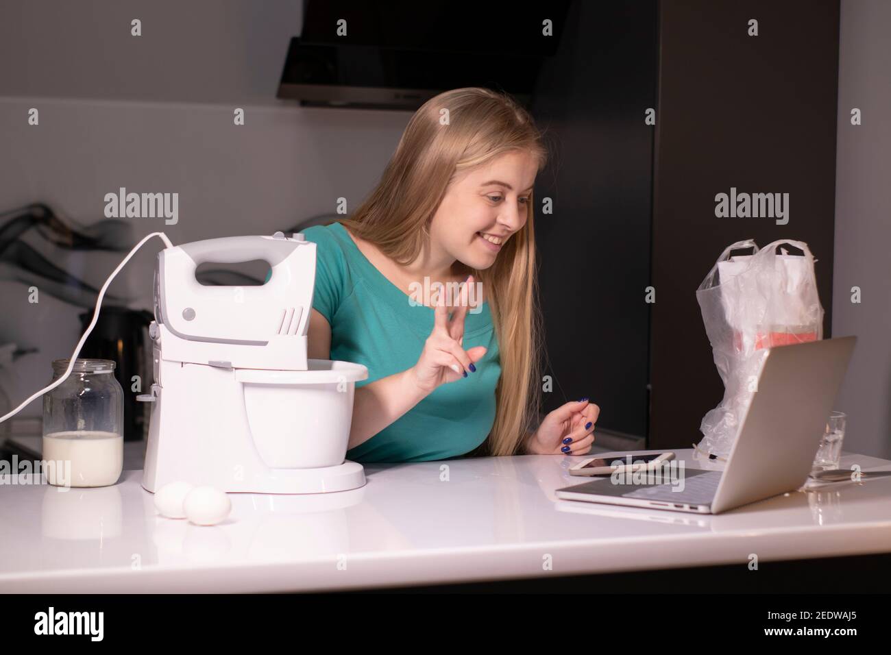 A blonde woman chef videoblogger cooking in the kitchen and filming ...