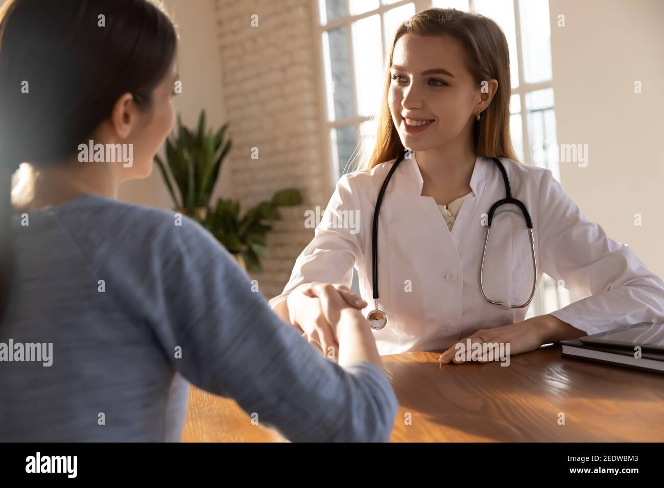 Young doctor shaking hands with happy female patient Stock Photo - Alamy