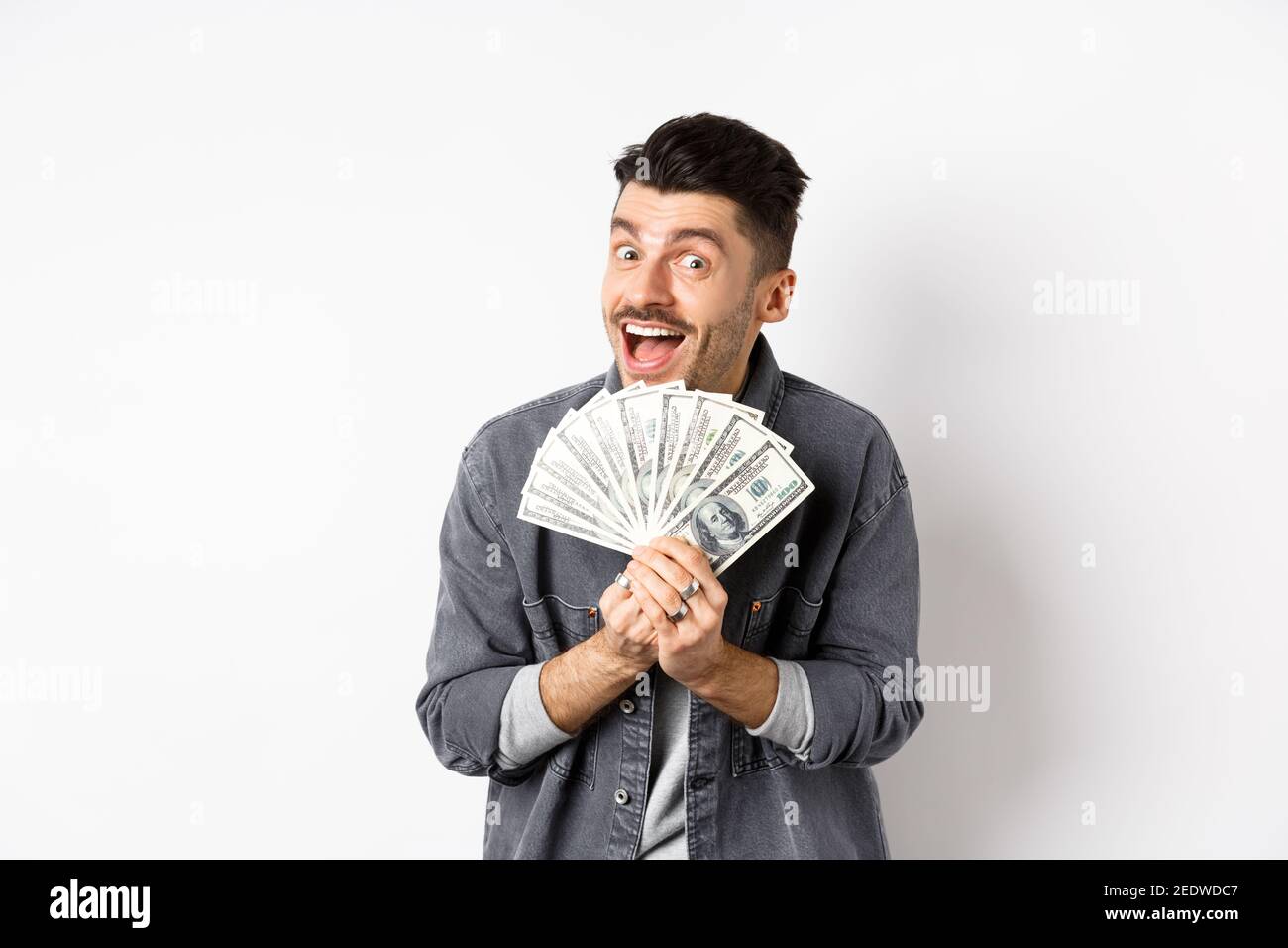 Excited young man smiling and showing dollar bills, making money ...