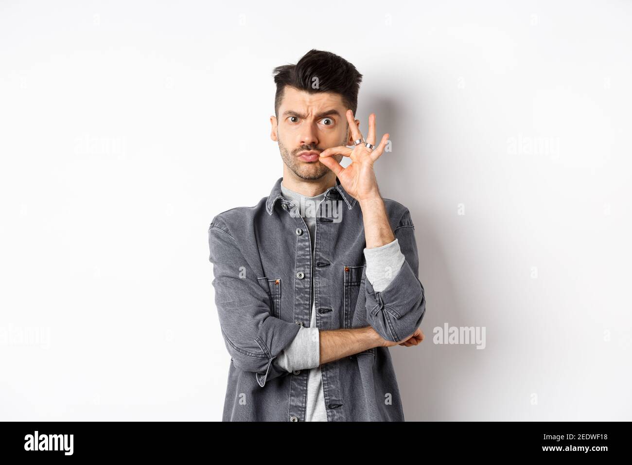 Serious man making zip gesture, tell to keep mouth shut, frowning and ...