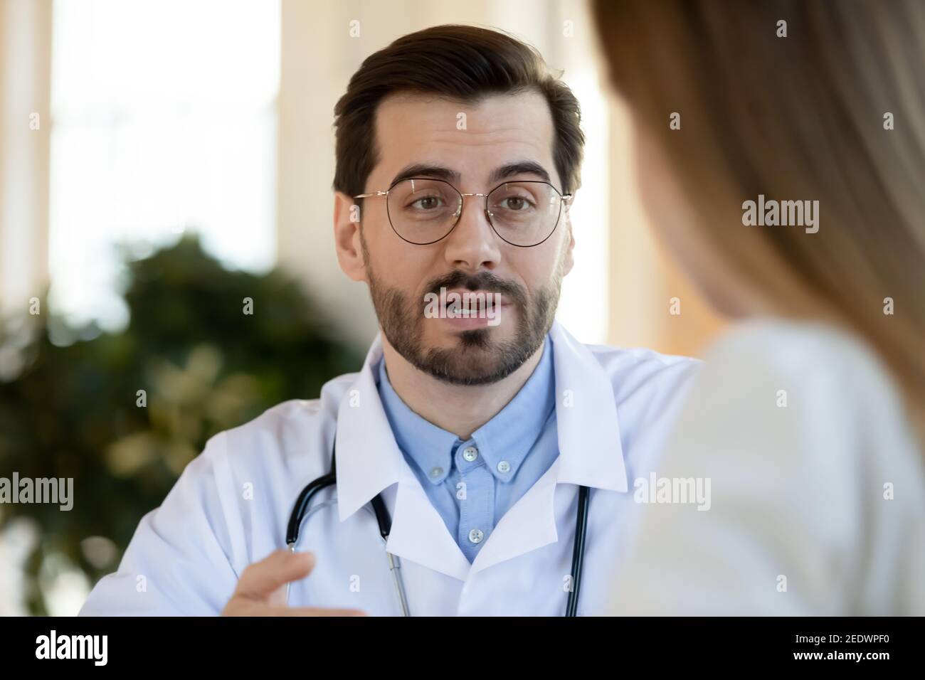 Focused young male doctor explaining healthcare treatment to patient ...