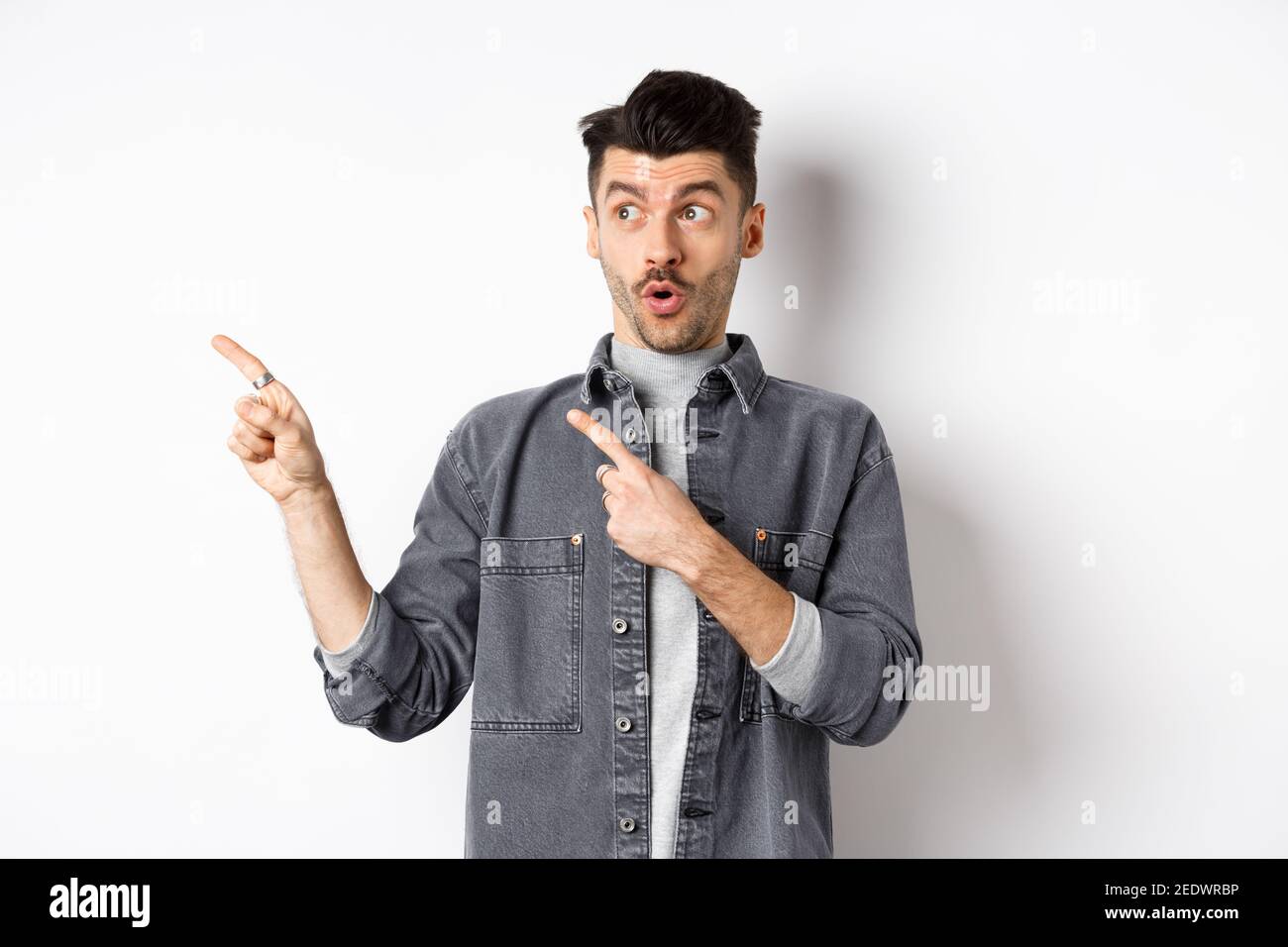 Stylish guy say wow, pointing and looking left with excited face ...