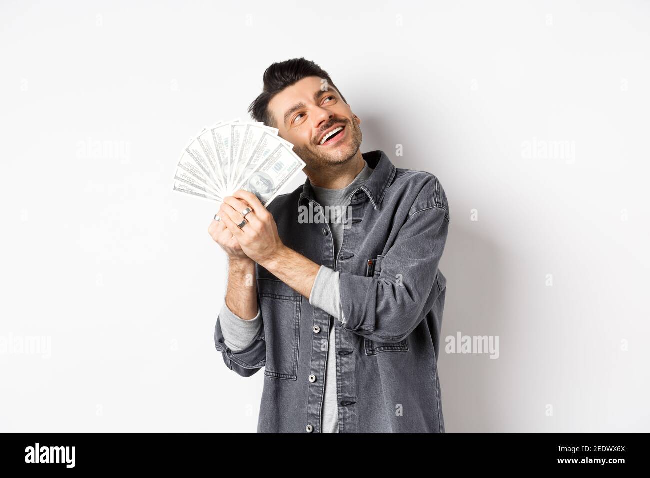 Happy rich guy hugging dollar bills and daydreaming, thinking of ...