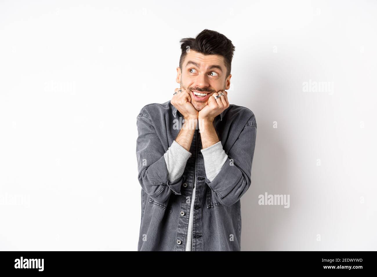 Excited cute young man look dreamy at upper left corner, waiting for ...